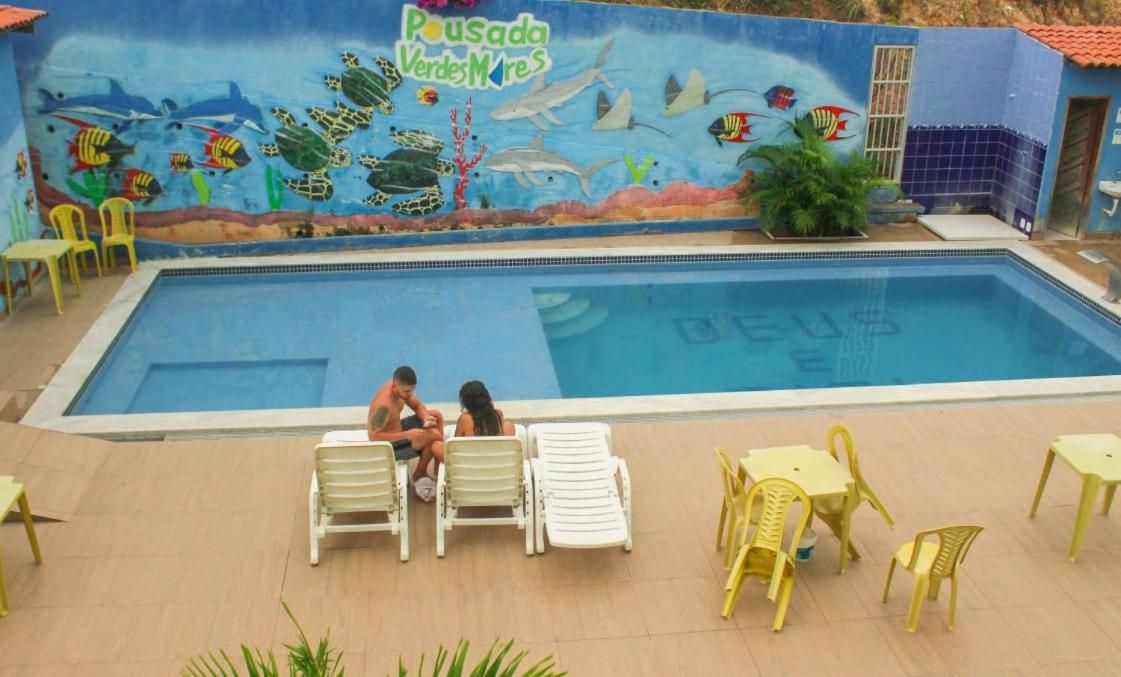 Piscina com um mural da vida marinha, cadeiras de descanso e deck revestido com azulejos.