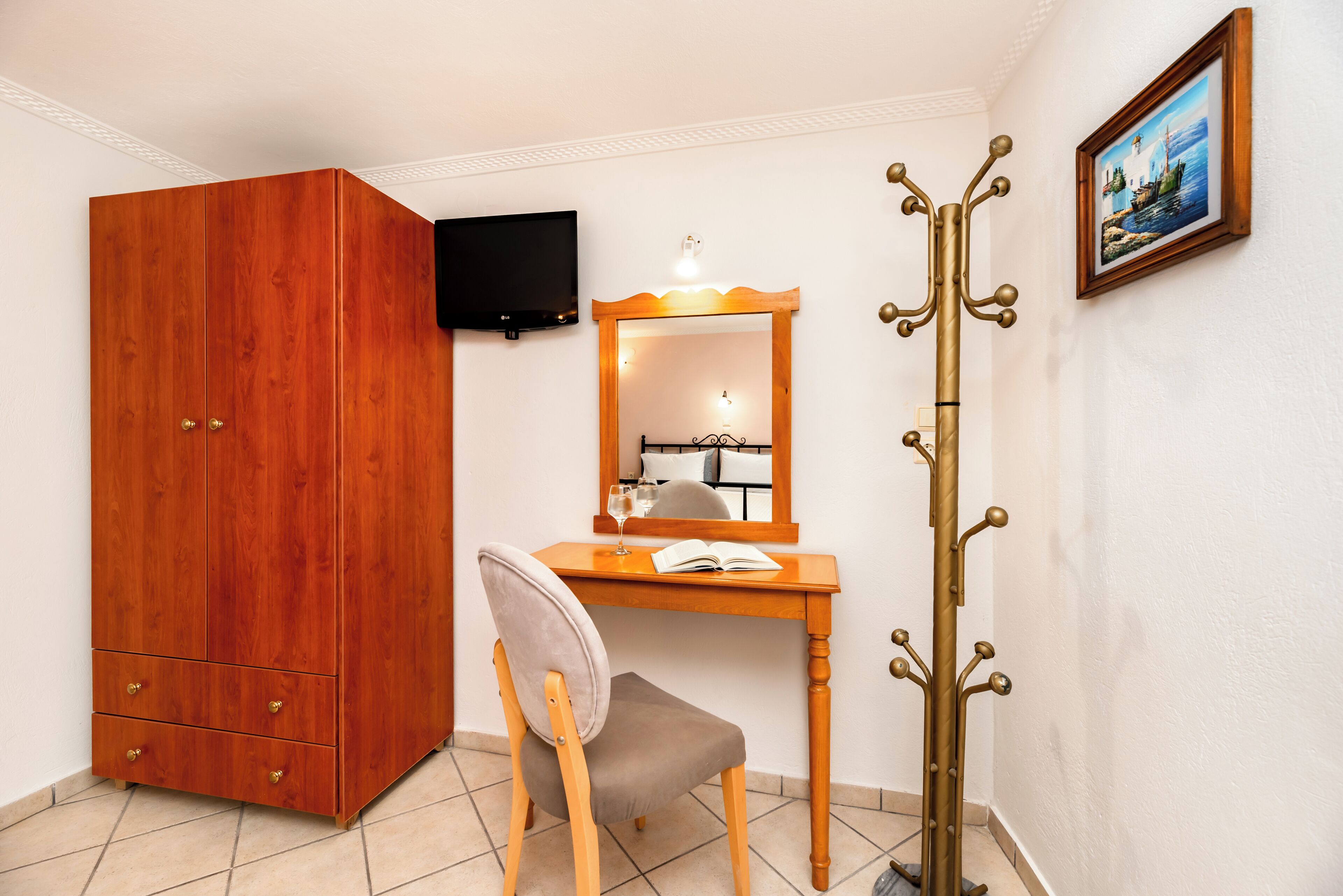Quarto com guarda-roupa de madeira, escrivaninha com espelho, cadeira e cabideiro.