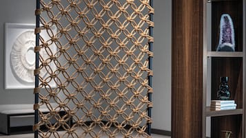 Um separador com corda em um quarto com uma estante e objetos decorativos.