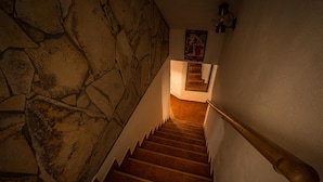 Uma escadaria com paredes de pedra e um corrimão de madeira.