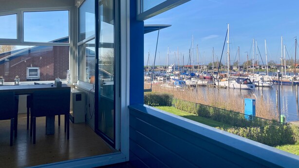 Quarto com grande janela vista para uma marina com barcos.