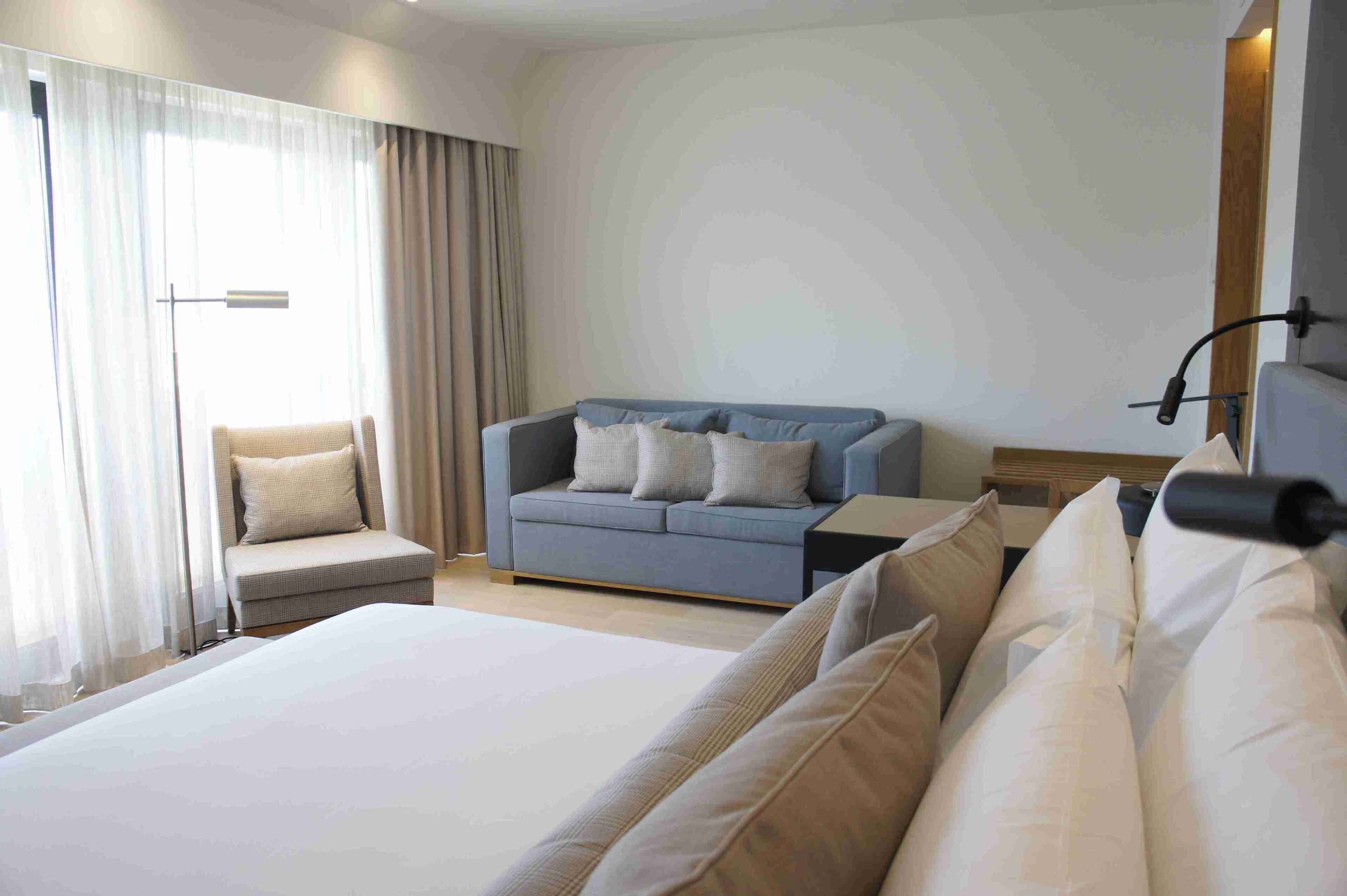 Quarto de hotel com uma cama grande, um sofá, uma cadeira e uma mesa.