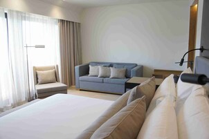Quarto de hotel com uma cama grande, um sofá, uma cadeira e uma mesa.