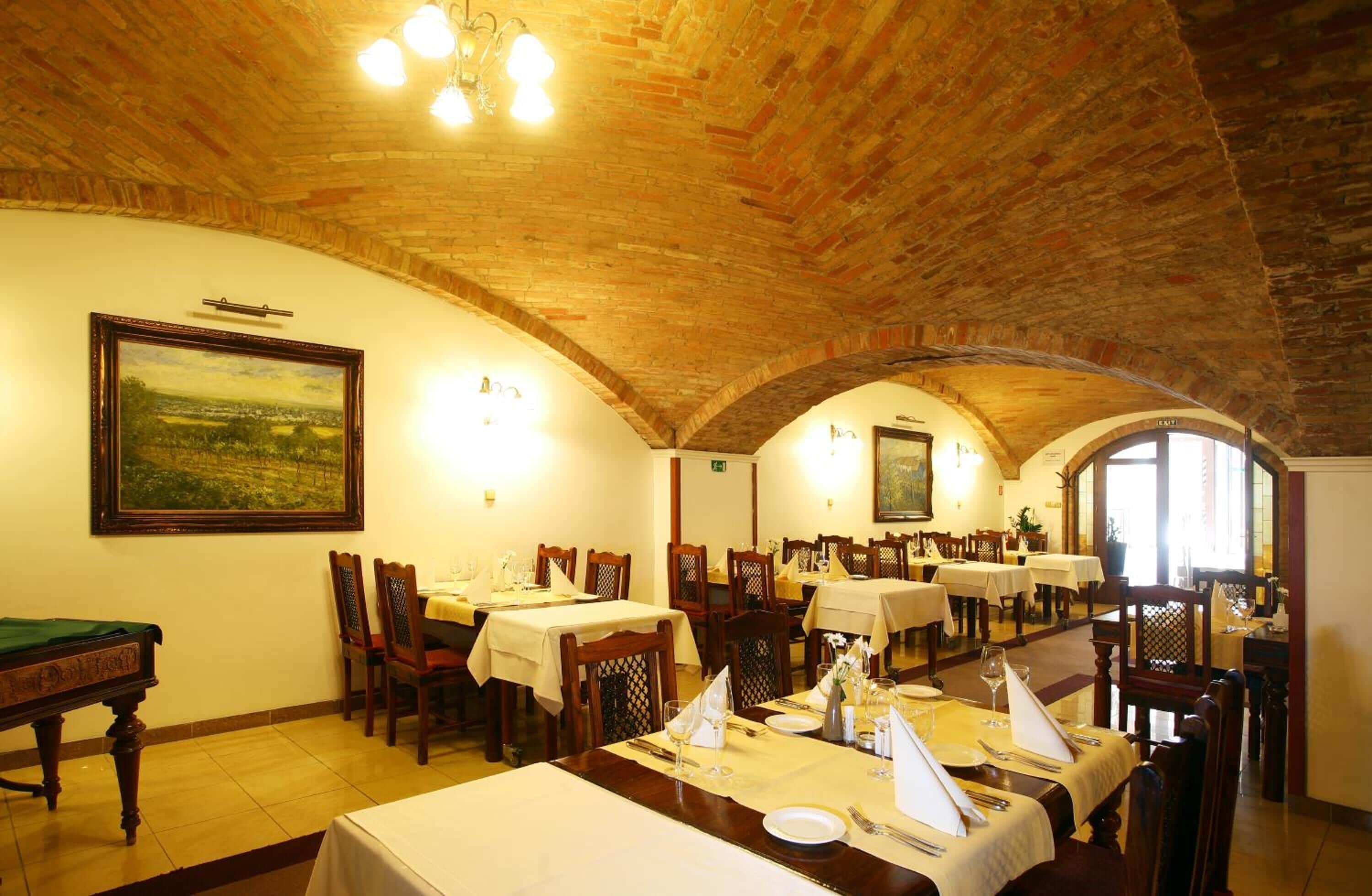 Um restaurante com arcos de tijolo, mesas e cadeiras de madeira.
