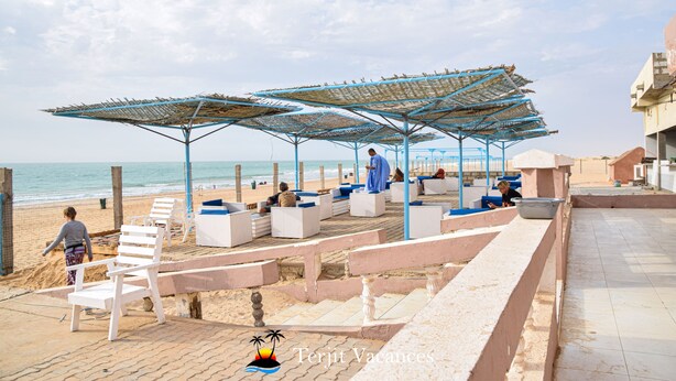 Um terraço à beira-mar com mobiliário de exterior, vista para o mar e chão em mosaico.