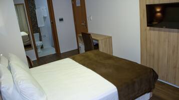 Um quarto com uma cama, uma escrivaninha e uma televisão.