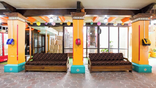 Um hall com dois sofás estampados, piso ladrilhado e teto colorido.
