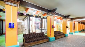 Um hall com sofás estampados, um telefone e piso ladrilhado.