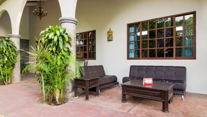 Um pátio espaçoso com um sofá de couro preto, uma mesa de centro de madeira e um vaso de planta.