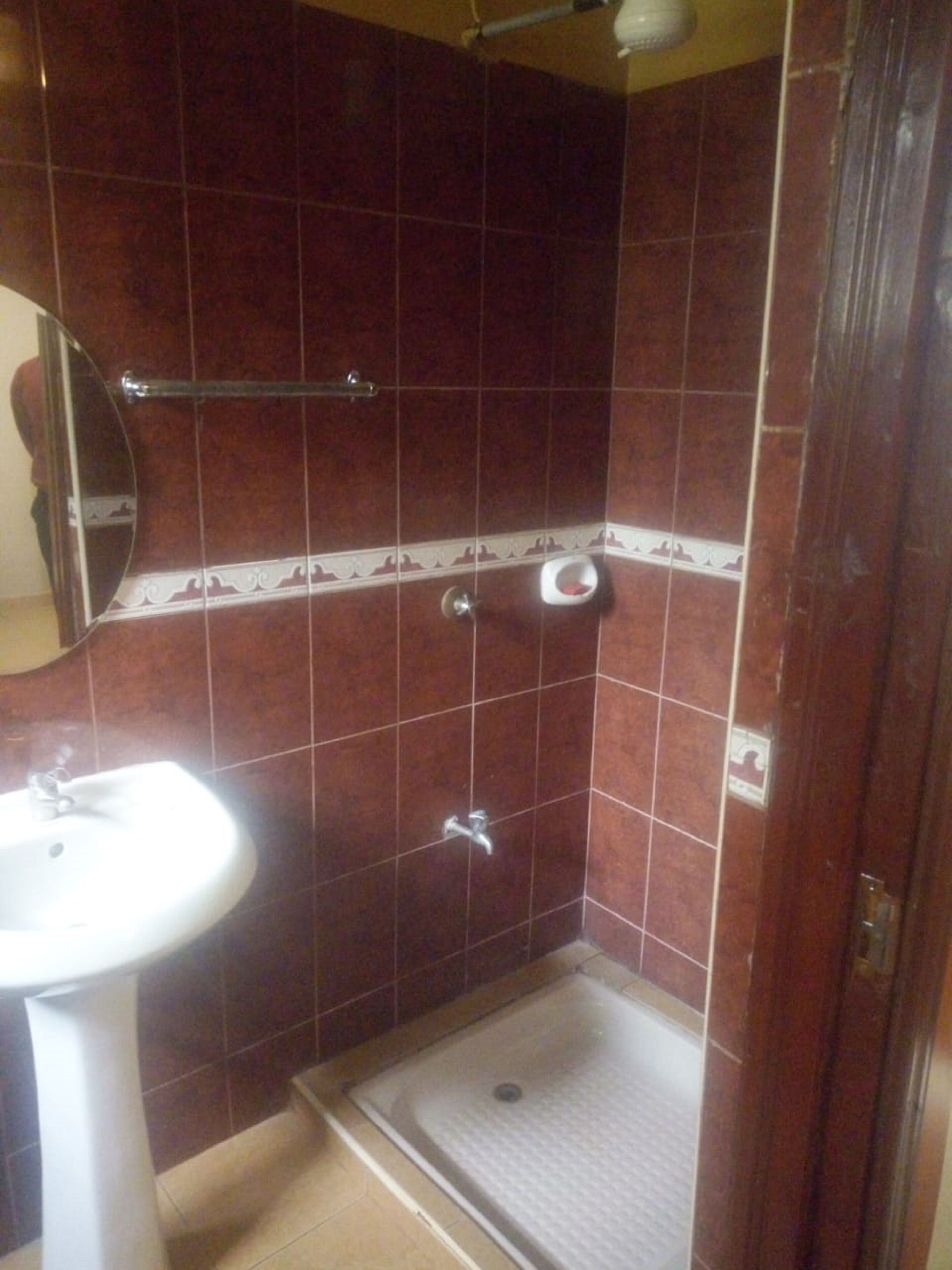 Casa de banho com uma pia branca, chuveiro com pavimento branco e espelho na parede.