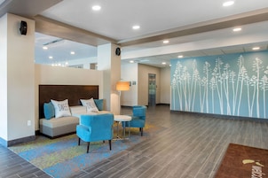 Um hall moderno com um sofá, cadeiras, uma luminária e uma parede com um padrão floral.