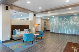Um hall moderno com um sofá, cadeiras, uma luminária e uma parede com um padrão floral.