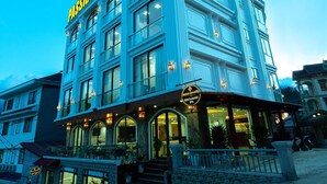 Um hotel com uma placa chamativa que diz "PASSION SAPA HOTEL" e uma entrada visível com degraus.