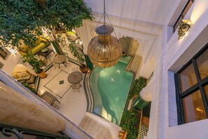 Um interior com vários níveis, piscina central, luminárias ornamentadas e escadaria.