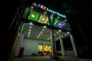 Um hotel chamado "Sky Lodge Ngapali" com fachada moderna, sinalização iluminada e uma entrada convidativa.