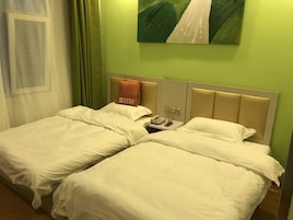 Quarto de hotel com duas camas, uma mesa de cabeceira com telefone e um quadro na parede.