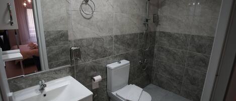 Uma casa de banho moderna com lavatório, sanita e chuveiro.