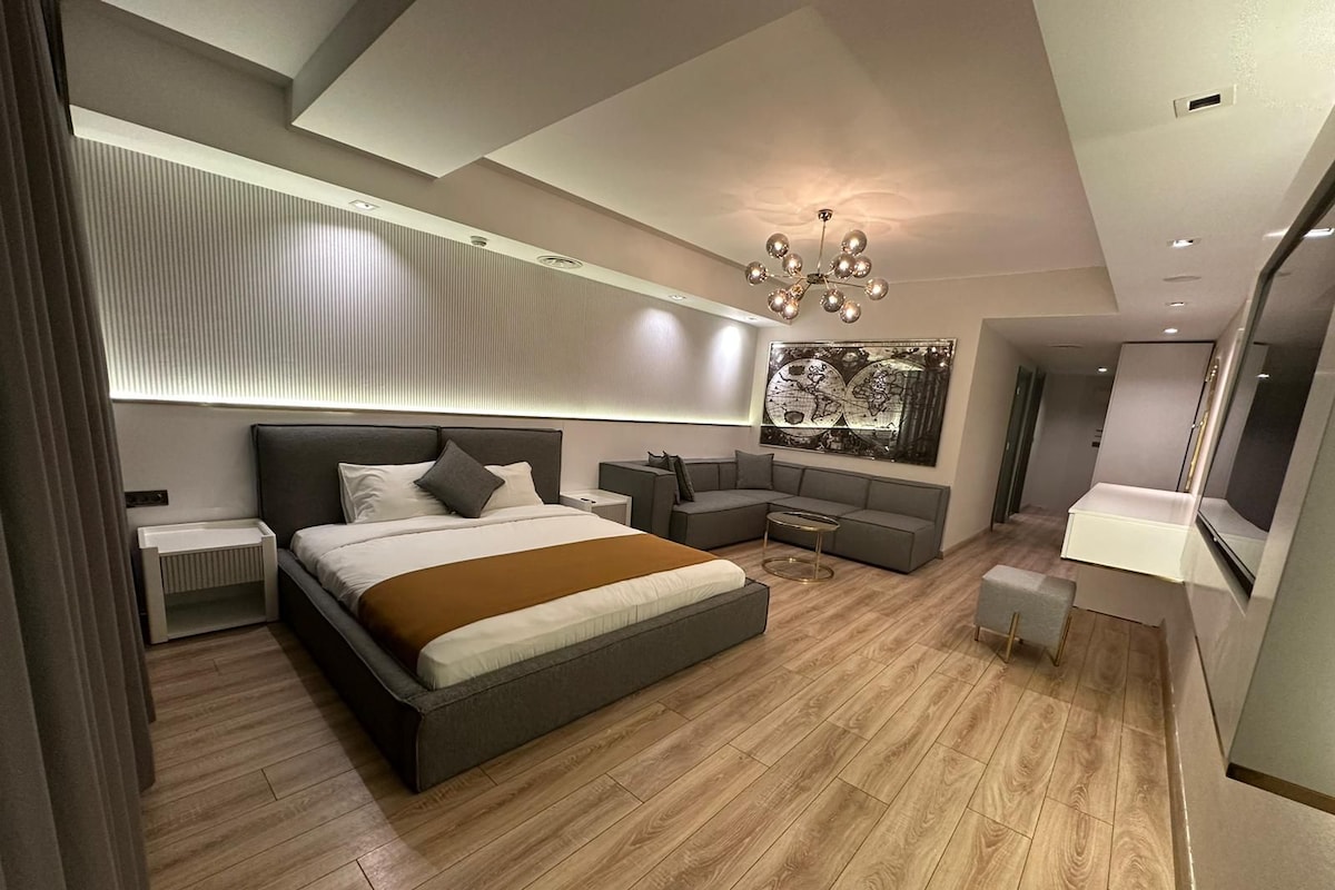 Quarto moderno com uma cama grande, um espaço de estar e uma mesa de jantar.