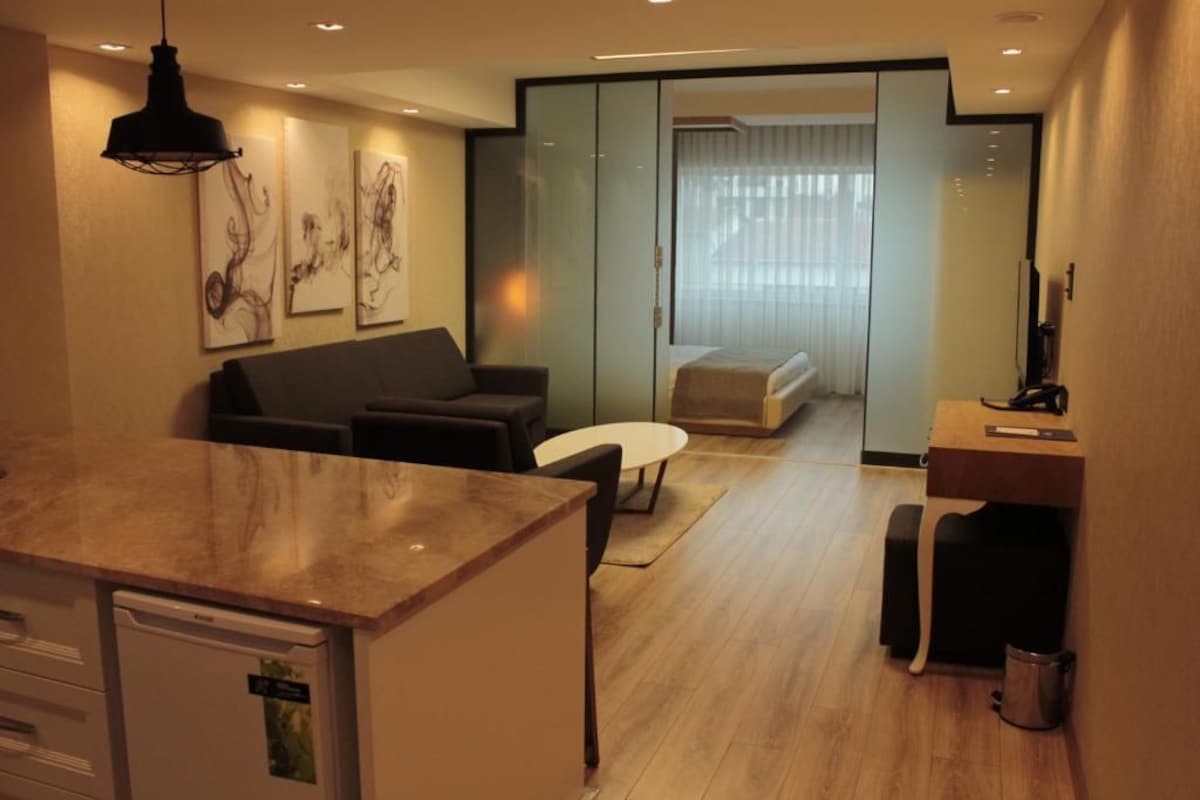 Quarto de hotel moderno com cozinha, mesa de jantar, sofá e cama com vista.