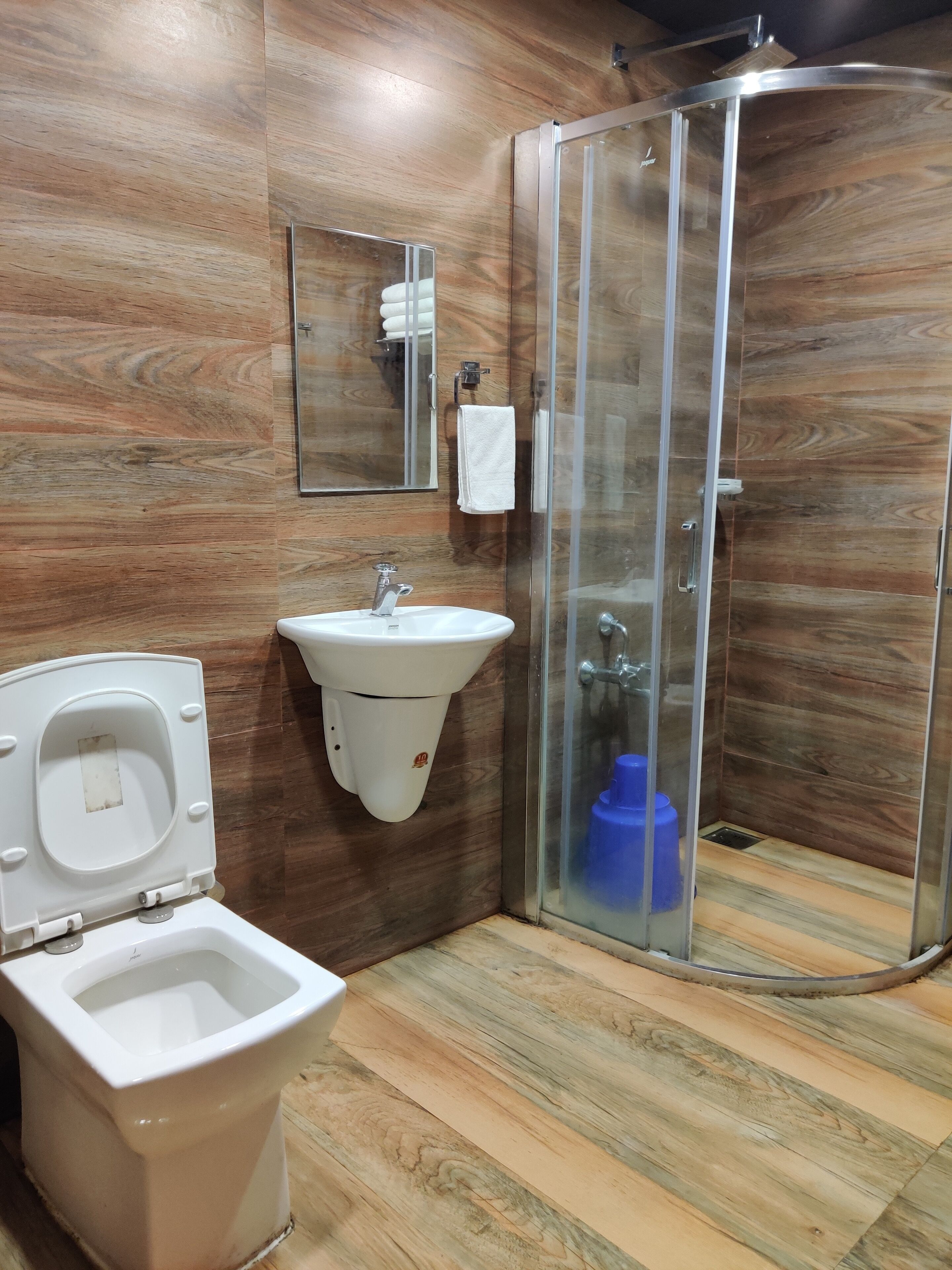 Casa de banho com sanita, lavatório e cabine de duche em vidro.