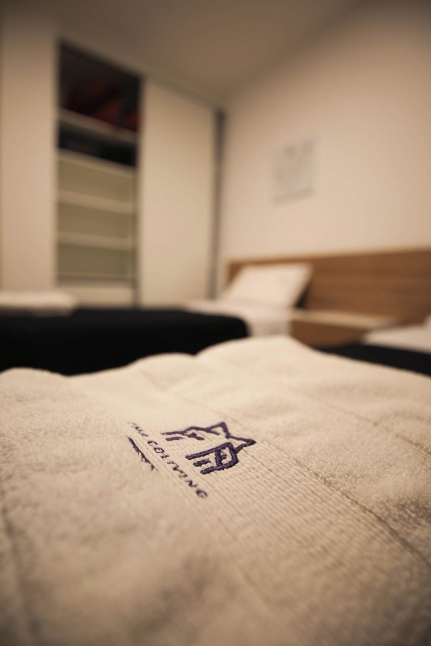 Um close-up de uma cama com um cobertor branco e um logotipo.