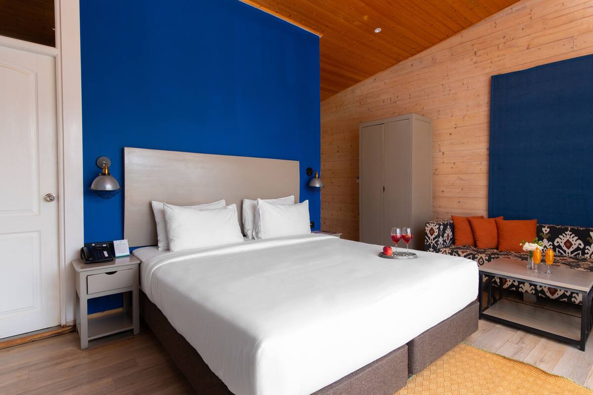 Quarto com uma cama grande, mesa de cabeceira, guarda-roupa, sofá e mesa de centro.
