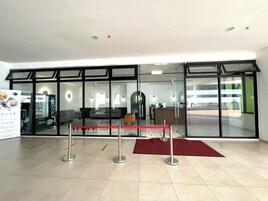 Um lobby moderno de hotel com balcão de recepção, área de estar e máquina de venda automática.