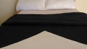 Uma cama com edredom preto e branco, um travesseiro branco e uma peça de roupa pendurada na parede.