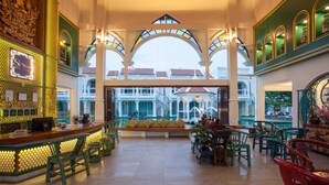 Um hall amplo com balcão de recepção, área de estar e grandes janelas em arco com vista para uma piscina.