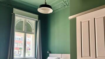 Quarto com cama, cadeira, janela com cortinas e porta.
