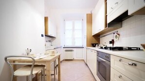 Uma cozinha compacta com mesa, cadeiras, fogão e armários.