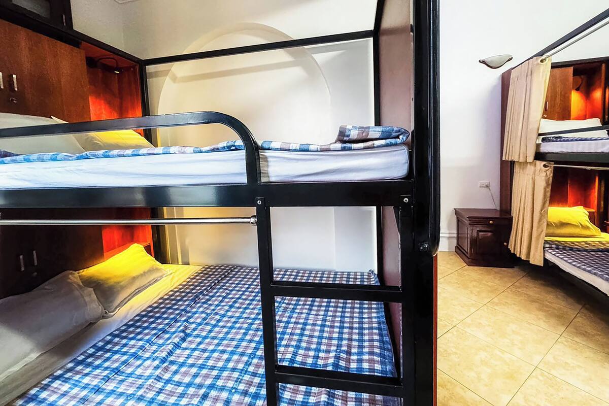 Quarto com beliche, guarda-roupa de madeira e uma pequena mesa.