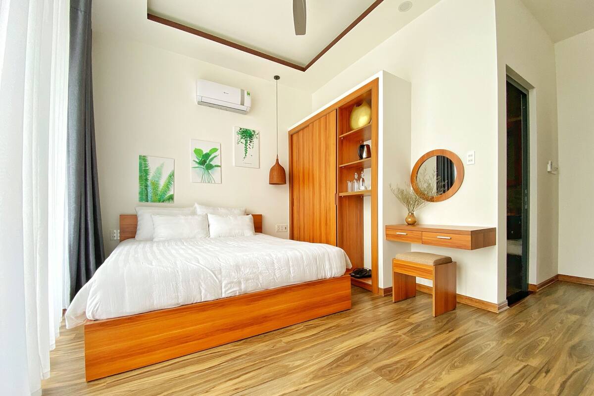 Quarto com estrutura de cama de madeira, mesa de cabeceira, guarda-roupa e espelho.