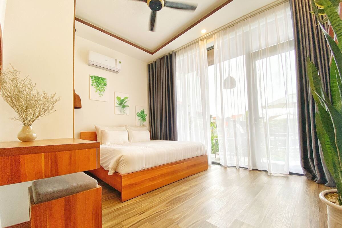 Quarto moderno com cama de madeira, uma escrivaninha e um vaso com planta.