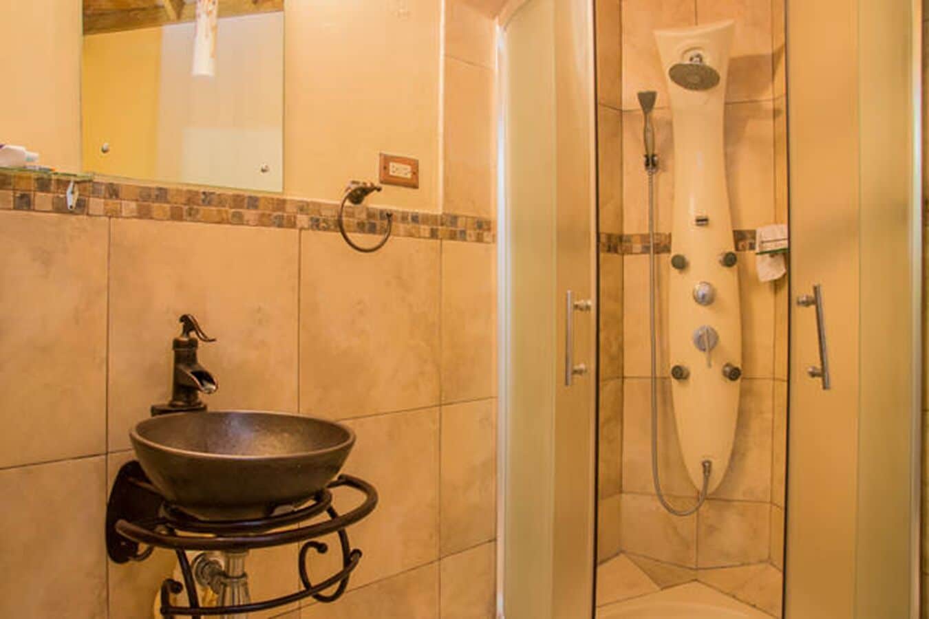 Uma casa de banho com lavatório grande, chuveiro com vários comandos e chão em azulejos.