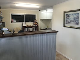 Uma área de recepção com balcão, estante, janela e quadro na parede.