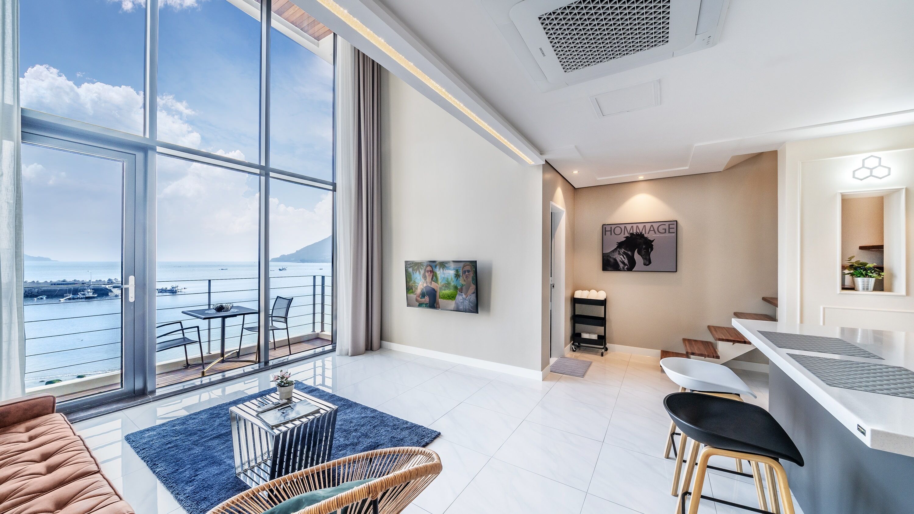 Sala de estar moderna com uma grande janela vista para um areal, área de jantar com bar, e uma obra de arte pendurada na parede.