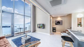 Sala de estar moderna com uma grande janela vista para um areal, área de jantar com bar, e uma obra de arte pendurada na parede.