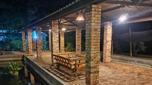 Uma área externa coberta com piscina, assentos de madeira e pilares de tijolo.