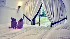 Cama com lençóis brancos, toalhas roxas e flores cor-de-rosa.