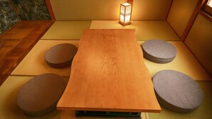 Um espaço com tatames, uma mesa de madeira e quatro almofadas.