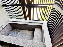 Um espaço ao ar livre pequeno e cercado, com chão de pedra e grade de metal.