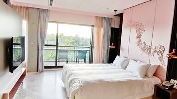 Quarto de hotel moderno com uma cama grande, televisão, varanda com vista e um elemento decorativo na parede.
