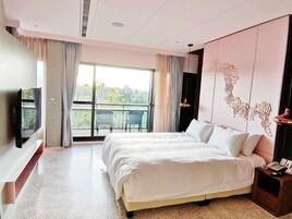 Quarto de hotel moderno com uma cama grande, televisão, varanda com vista e um elemento decorativo na parede.