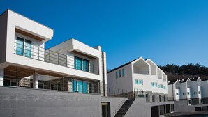 Um edifício moderno com telhado plano, grandes janelas e uma escadaria que leva a um nível inferior.