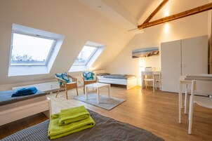 Quarto moderno no estilo loft, com teto inclinado, claraboias, cama, escrivaninha e guarda-roupa.