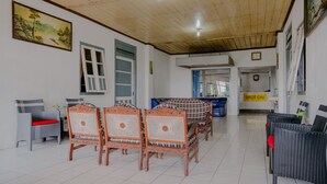 Quarto espaçoso com teto alto, mobiliário de vime e um aviso com a inscrição 'SPOT ON'.