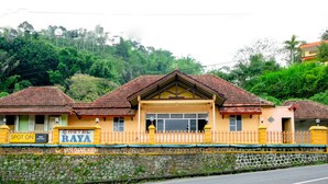 Um edifício amarelo com uma placa que diz "HOTEL RAYA" e uma parede de pedra na frente.