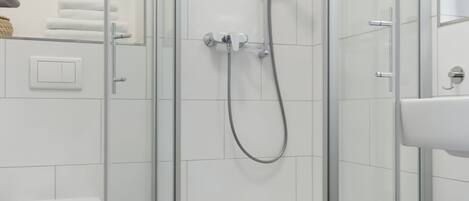 Uma casa de banho moderna com cabine de duche em vidro, sanita branca e lavatório.