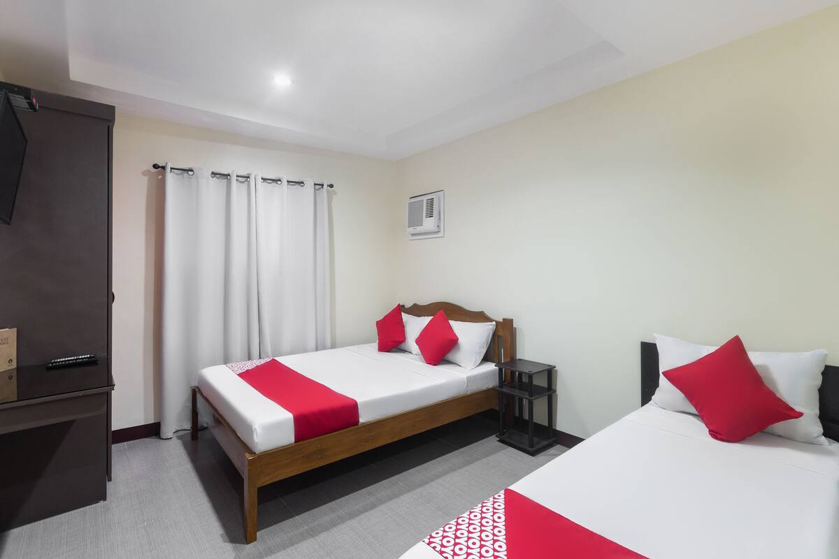 Quarto de hotel com uma cama de casal, uma escrivaninha e um guarda-roupa.
